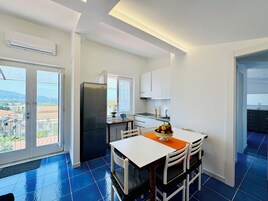 Uma cozinha moderna com geladeira preta, armários brancos e um espaço de refeições com mesa e cadeiras.