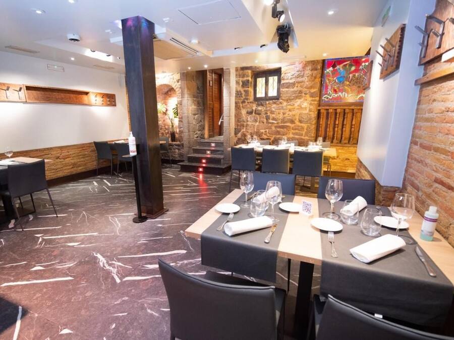 Restaurante com piso de mármore, paredes de pedra e mobiliário moderno.