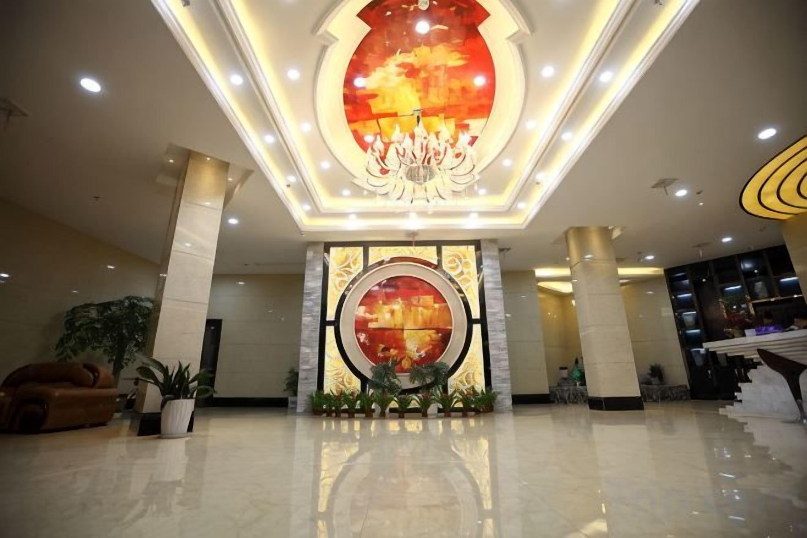 Um hall de hotel com uma grande obra de arte circular, um candelabro e uma recepção.