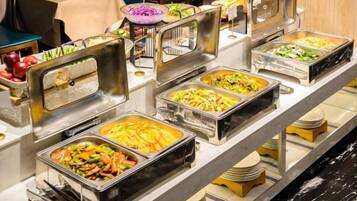 Buffet com diversas estações de comida, incluindo um bar de saladas e uma área de pratos quentes.