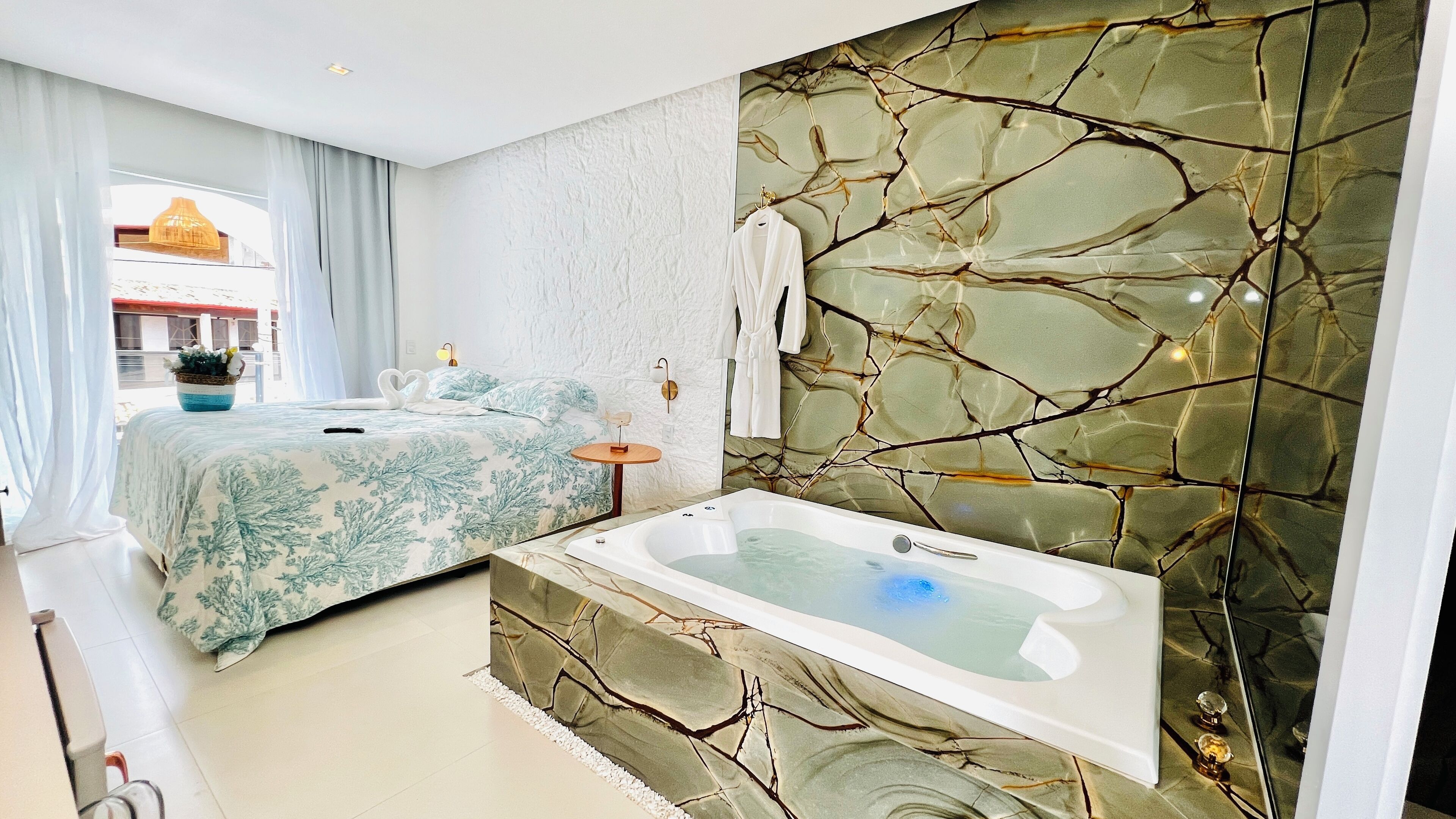 Quarto com cama, banheira e parede de pedra.