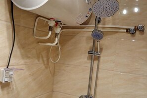 Um chuveiro com um chuveiro manual, uma torneira fixada na parede e um painel de controle.