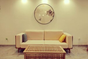Sala de estar moderna com sofá, mesa de centro e obra de arte circular pendurada na parede.