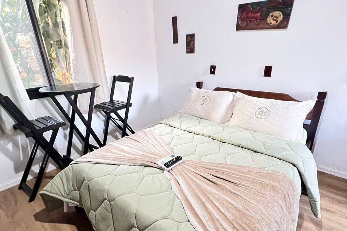 Um quarto com cama, escrivaninha e cadeiras.