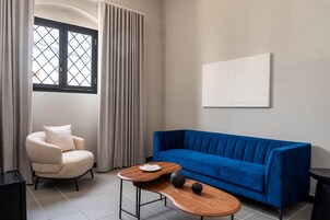 Uma sala de estar moderna com um sofá azul, uma poltrona branca e uma mesa de centro de madeira.