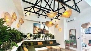 Uma sala de estar moderna com um sofá verde, um tapete xadrez e luminárias de vime pendentes.