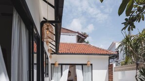 Uma área de piscina privativa com espreguiçadeira, um espaço de estar pequeno e vista para um edifício com telhado ladrilhado.