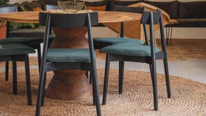 Uma sala de jantar moderna com mesa de madeira, cadeiras pretas e luminárias pendentes trançadas.