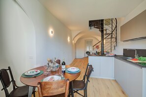 Uma sala de jantar com mesa de madeira, cadeiras e uma cozinha com escada em espiral.