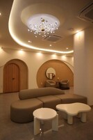 Um interior moderno com teto curvo, iluminação embutida, sofá modular e uma mesa redonda.