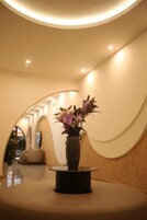 Um interior moderno com uma mesa redonda, um vaso com flores e uma parede curva.