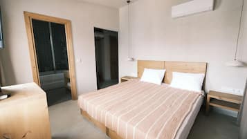 Quarto com cama de madeira, mesas de cabeceira, televisão e ar condicionado.