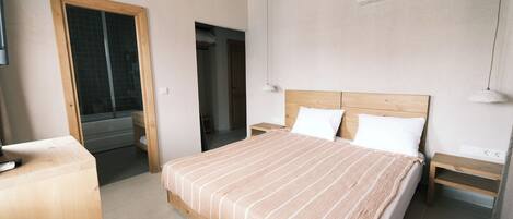 Quarto com cama de madeira, mesas de cabeceira, televisão e ar condicionado.