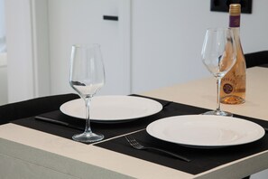Uma mesa de jantar com dois pratos brancos, duas taças de vinho e uma garrafa de vinho.