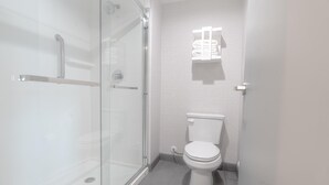 Uma casa de banho moderna com cabine de duche em vidro, sanita e um porta-toalhas.