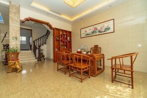 Um hall com escada, móveis de madeira, um quadro floral emoldurado e um vaso de planta.