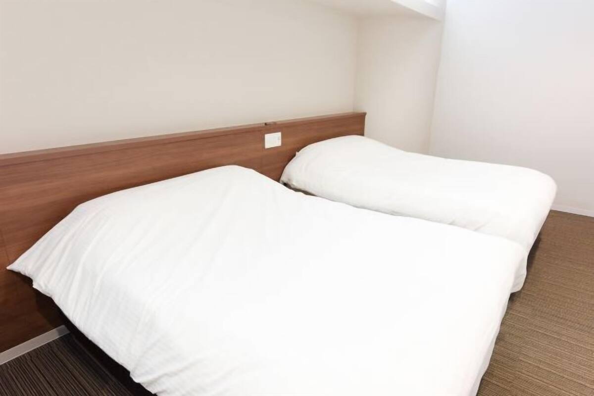 Uma cama de solteiro com cabeceira de madeira em quarto de hotel.