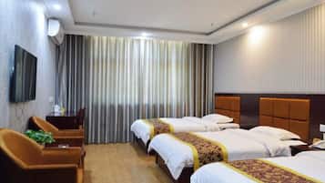 Quarto de hotel com três camas, televisão, escrivaninha e uma cadeira.