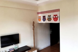 Quarto com televisão de tela plana, um bastão de madeira e uma parede com decoração de corujas.