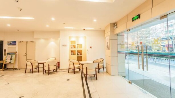 Um saguão de hotel com parede de vidro, balcão de recepção e área de estar.