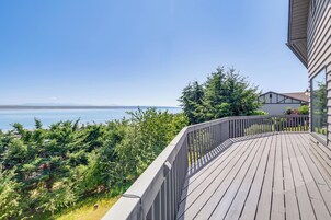 Um deck de madeira com guarda-corpo, com vista para um corpo d'água e vegetação densa.