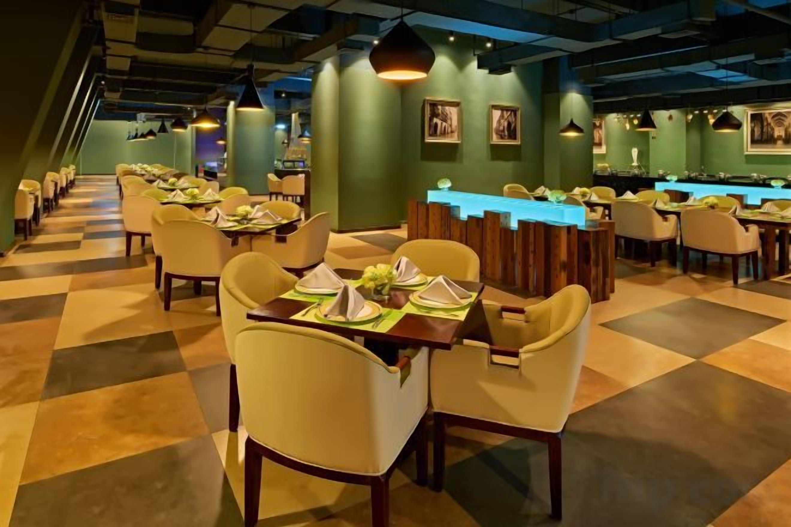 Restaurante com várias mesas, cadeiras, um balcão e uma área de recepção.