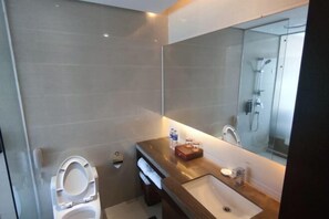 Uma casa de banho moderna com sanita, lavatório e chuveiro.
