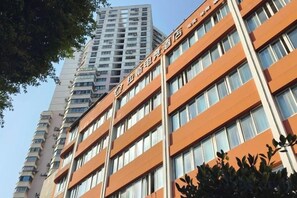Um edifício de vários andares com design arquitetônico moderno, com uma série de janelas e uma placa de destaque.