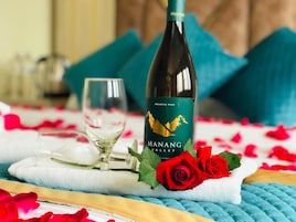 Uma garrafa de vinho do Vale do Manang, uma taça e uma rosa sobre uma toalha.
