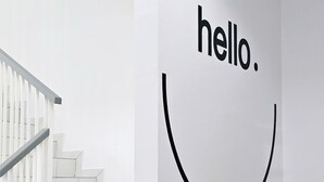 Uma escadaria com corrimãos brancos e uma parede com o texto simples 'hello' e um rosto sorridente.