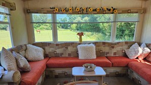 Uma sala de estar aconchegante com um sofá, uma mesa pequena e vista para uma paisagem verde.