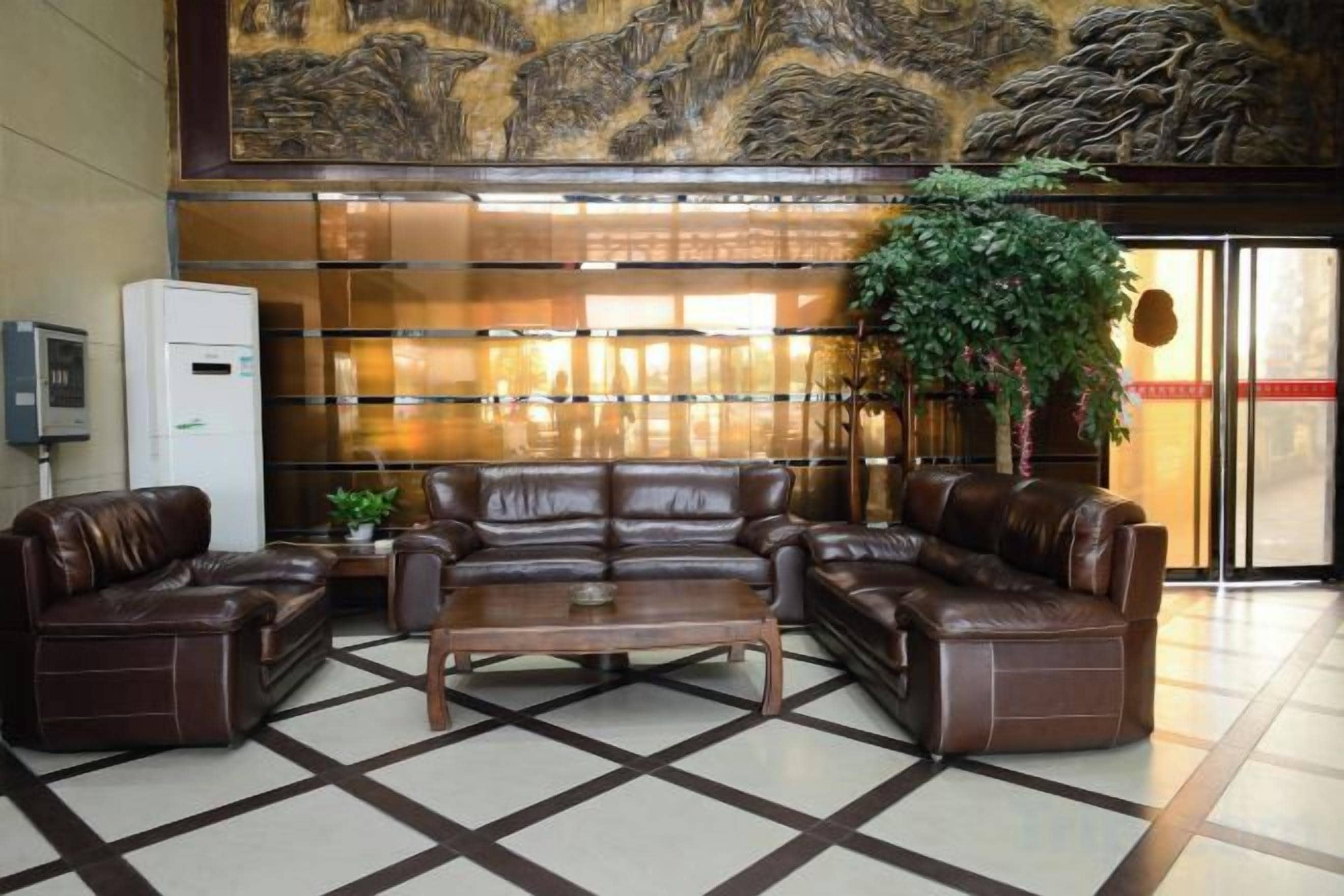 Um saguão com balcão de check-in, recepção e área de estar com sofás de couro e mesa de centro.