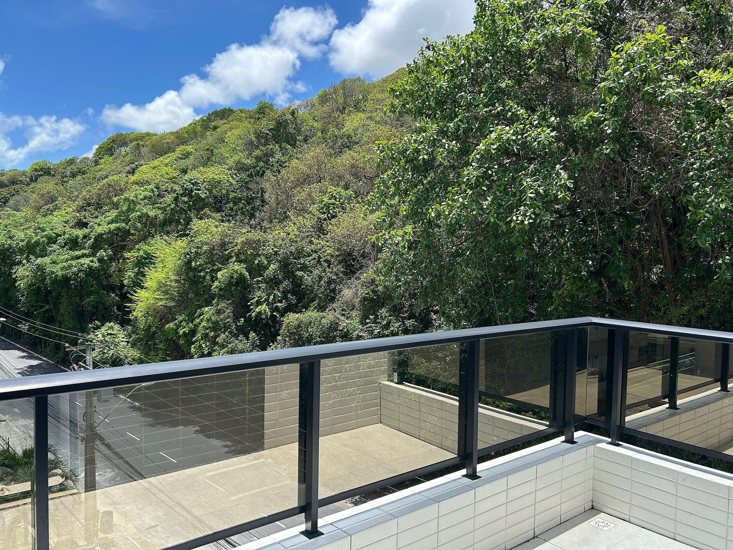 Uma varanda com vista para uma encosta verdejante.