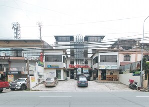Vista da rua com um edifício que abriga uma farmácia, um restaurante e um espaço de escritório.