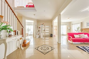 Uma sala de estar espaçosa com escada, um sofá vermelho vibrante e um console branco.