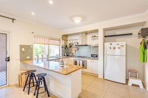 Uma cozinha moderna com uma ilha central, banquetas, geladeira e micro-ondas.