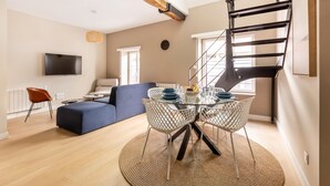 Uma sala de estar moderna com área de jantar, sofá, televisão e escada.