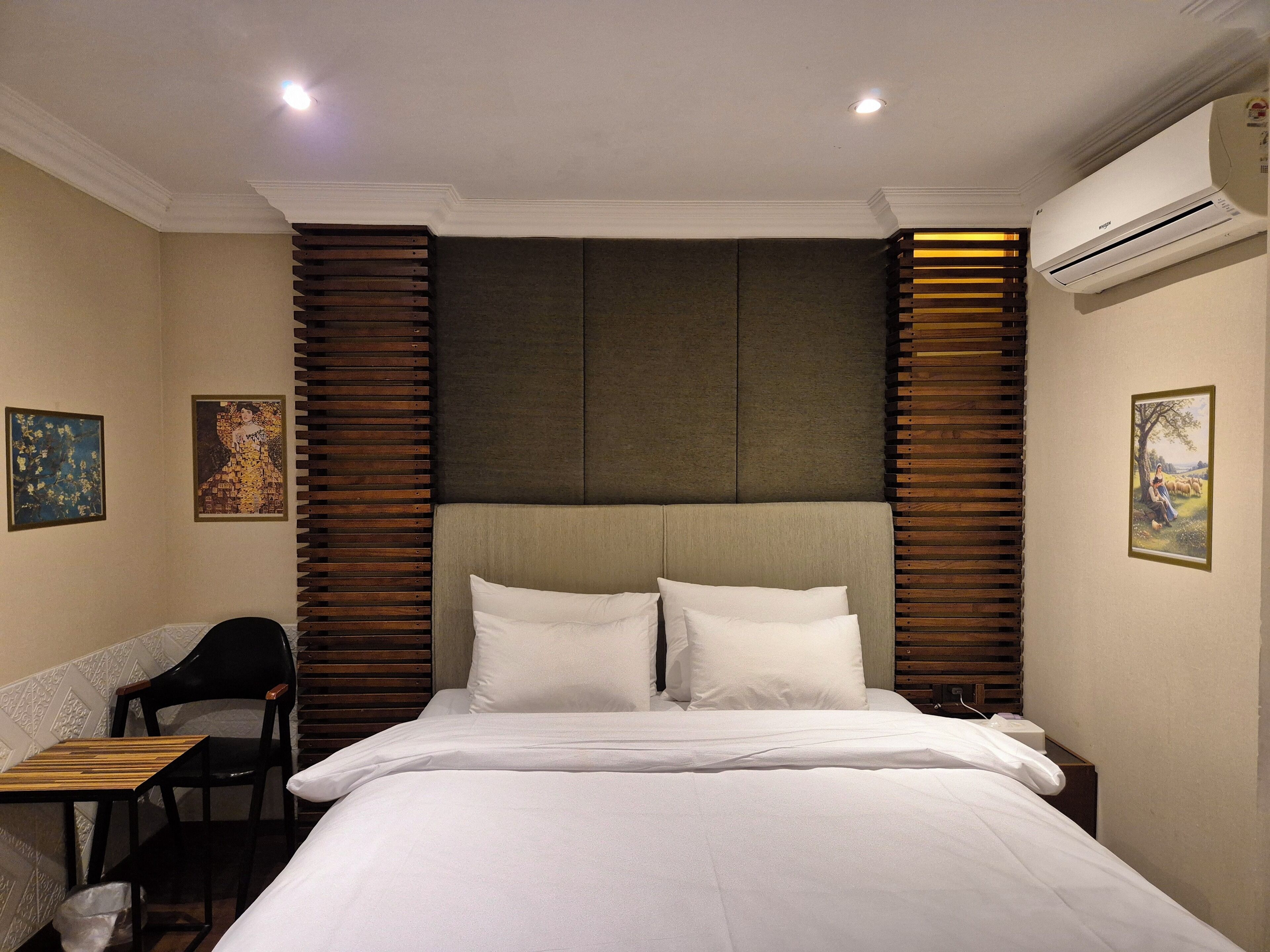 Quarto de hotel com uma cama grande, uma escrivaninha e uma cadeira.