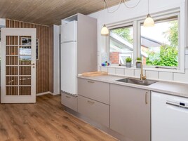 Uma cozinha moderna com uma lava-louças Bosch embutida, piso de madeira e uma janela com vista para um jardim.