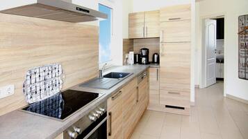 Cozinha moderna com fogão embutido, forno e exaustor de aço inoxidável.