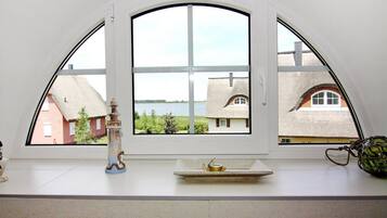 Quarto com uma grande janela em arco com vista para a água e edifícios.