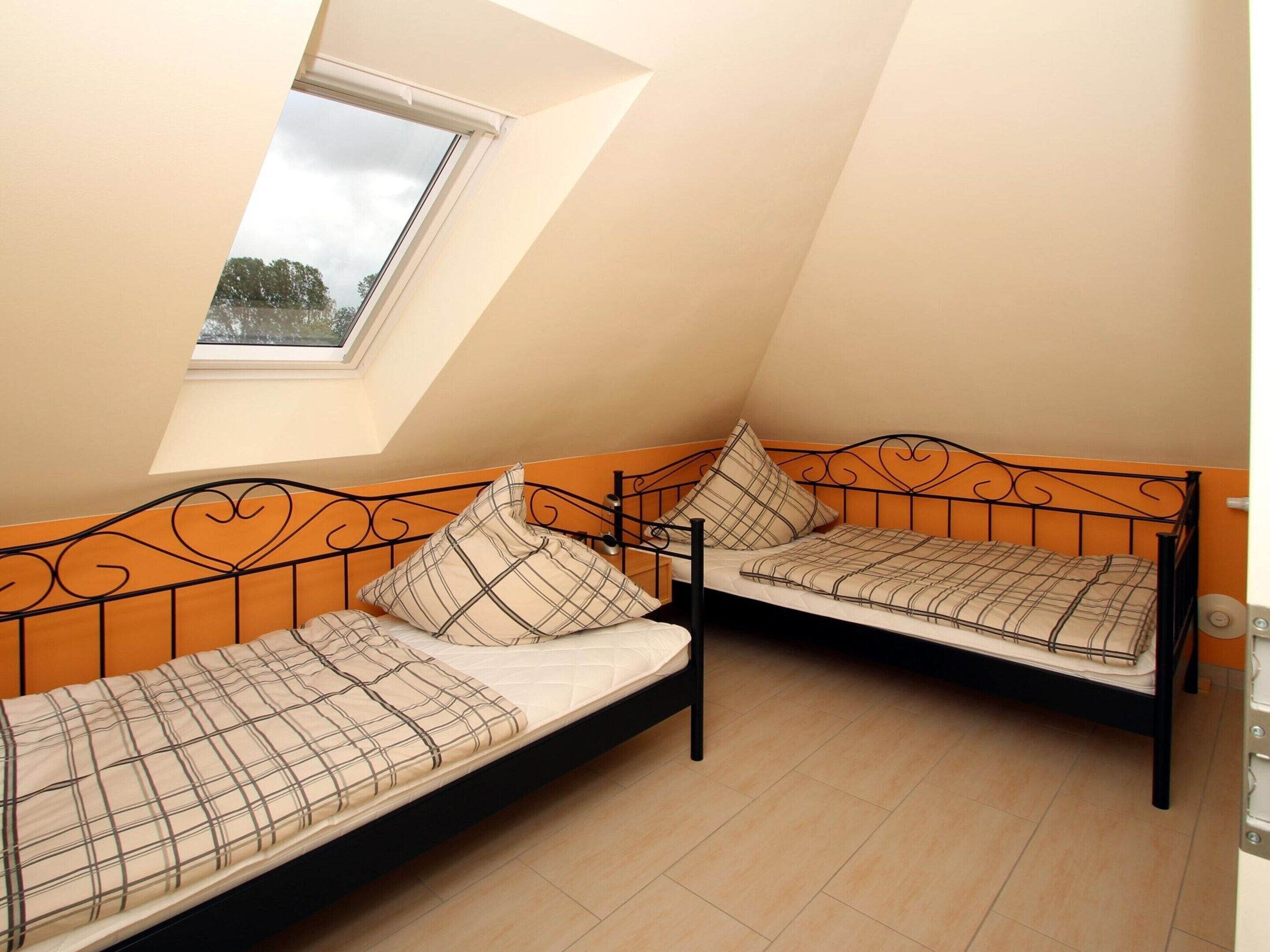 Um pequeno apartamento de um quarto, com duas camas, um claraboia e vista para árvores.