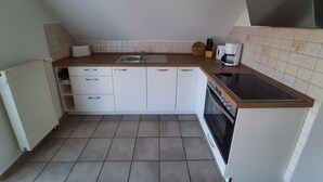 Uma cozinha compacta com armários brancos, pia, torradeira, cafeteira e forno.