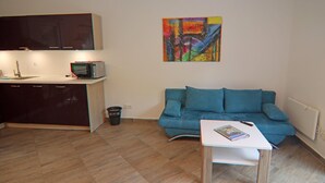 Um espaço compacto com cozinha americana, um sofá azul e uma mesa pequena.
