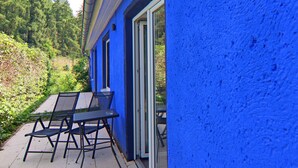 Edifício azul com área de varanda, com mesa e cadeiras.