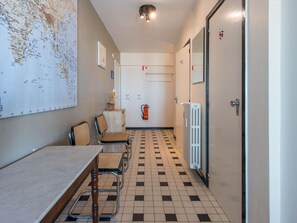 Um corredor com um mapa na parede, um radiador, um extintor de incêndio e uma porta.
