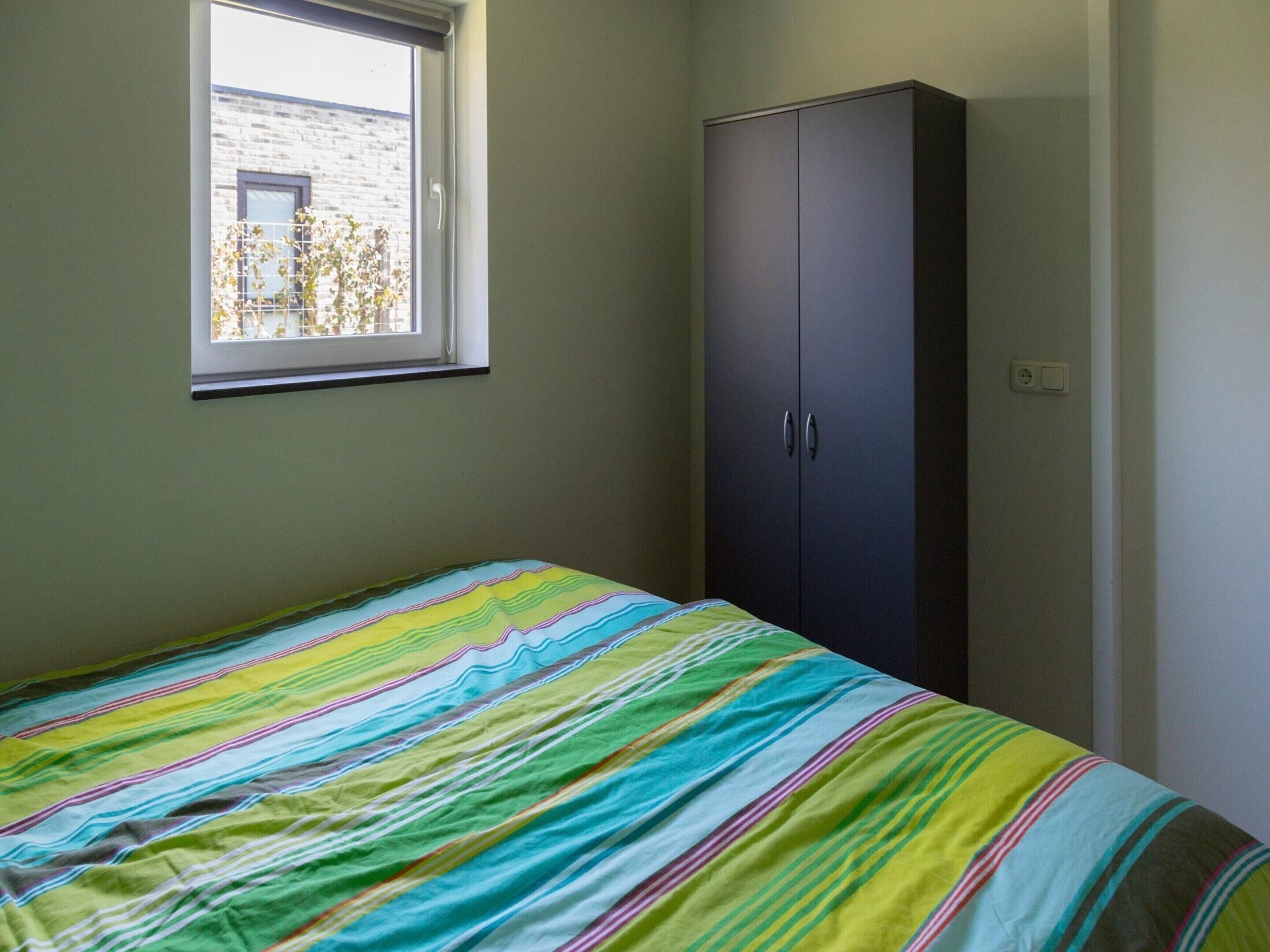 Quarto com cama, janela e guarda-roupa.