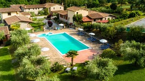 Uma área de piscina com uma piscina retangular, espreguiçadeiras e guarda-sóis.