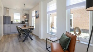 Cozinha moderna com área de jantar, janelas amplas e vista para um edifício de tijolos.
