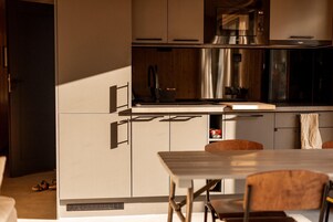 Cozinha moderna com eletrodomésticos de aço inoxidável, armários de madeira e um espaço de jantar com mesa e cadeiras.
